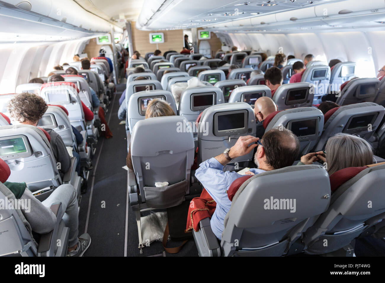Interior of large commercial airplane with passengers on their seats ...