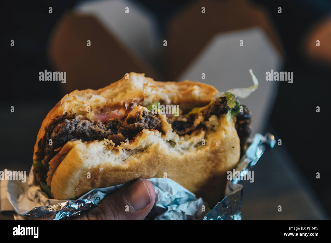 Personal perspective of man eating greasy cheeseburger Stock Photo - Alamy