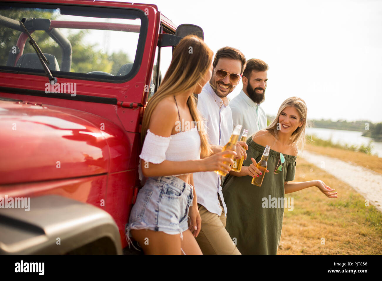 Young people drinking and having fun by car outdoor at hot summer day ...