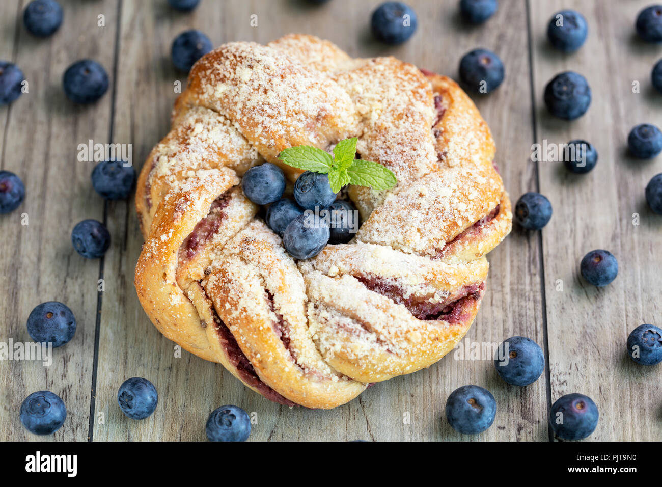 Blueberry pleated bun with powdered sugar and fresh berries Stock Photo ...