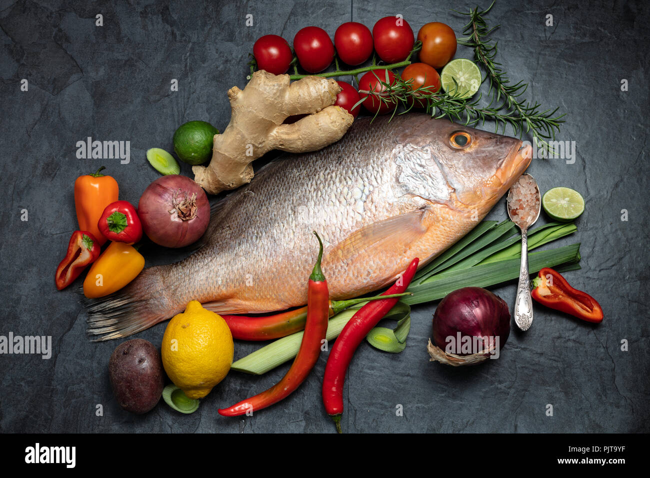 Fresh raw red snapper fish with spices, herbs and vegetables for ...