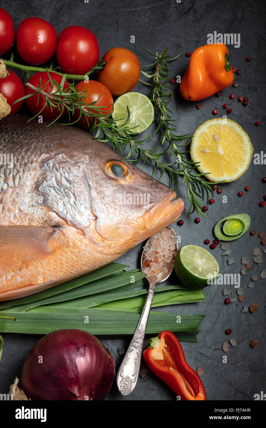 Fresh raw red snapper fish with spices, herbs and vegetables for ...