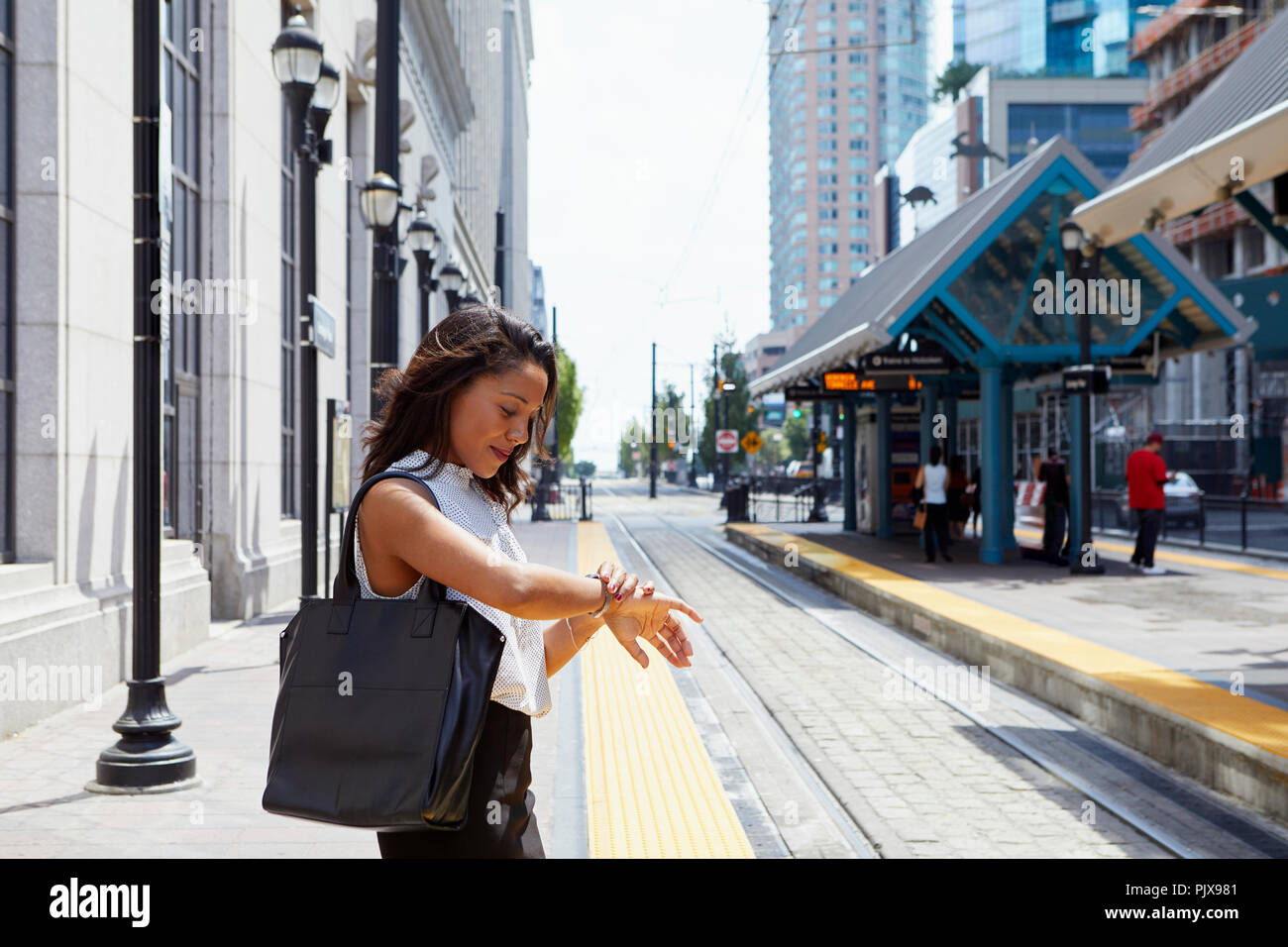 Businesswoman checking time by light rail line Stock Photo - Alamy