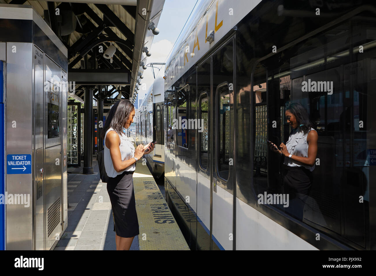Businesswoman using cellphone in train station Stock Photo - Alamy