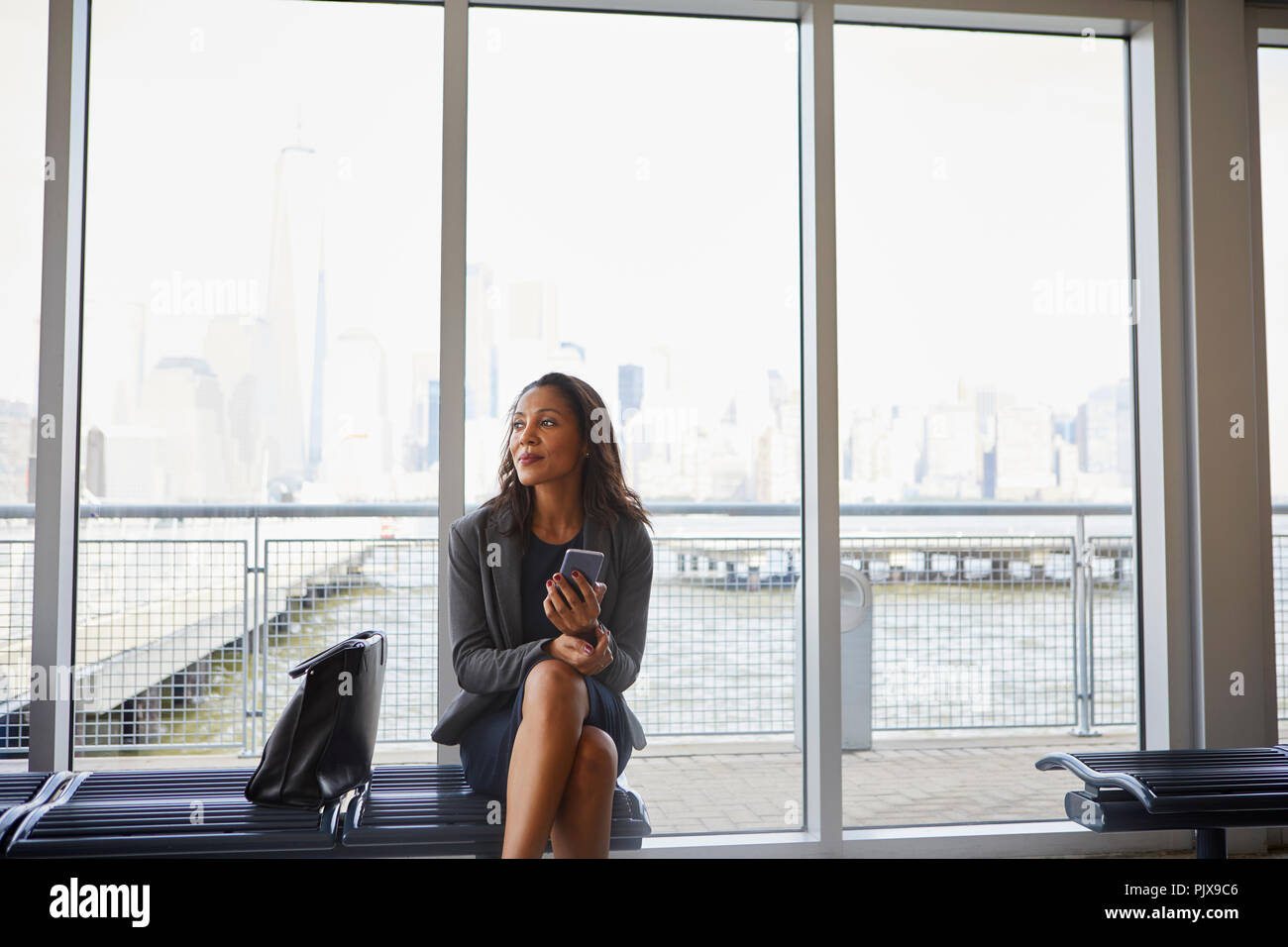 Businesswoman using cellphone inside ferry terminal Stock Photo - Alamy