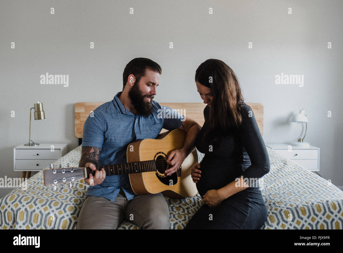 Man playing guitar to baby in wife's belly Stock Photo - Alamy