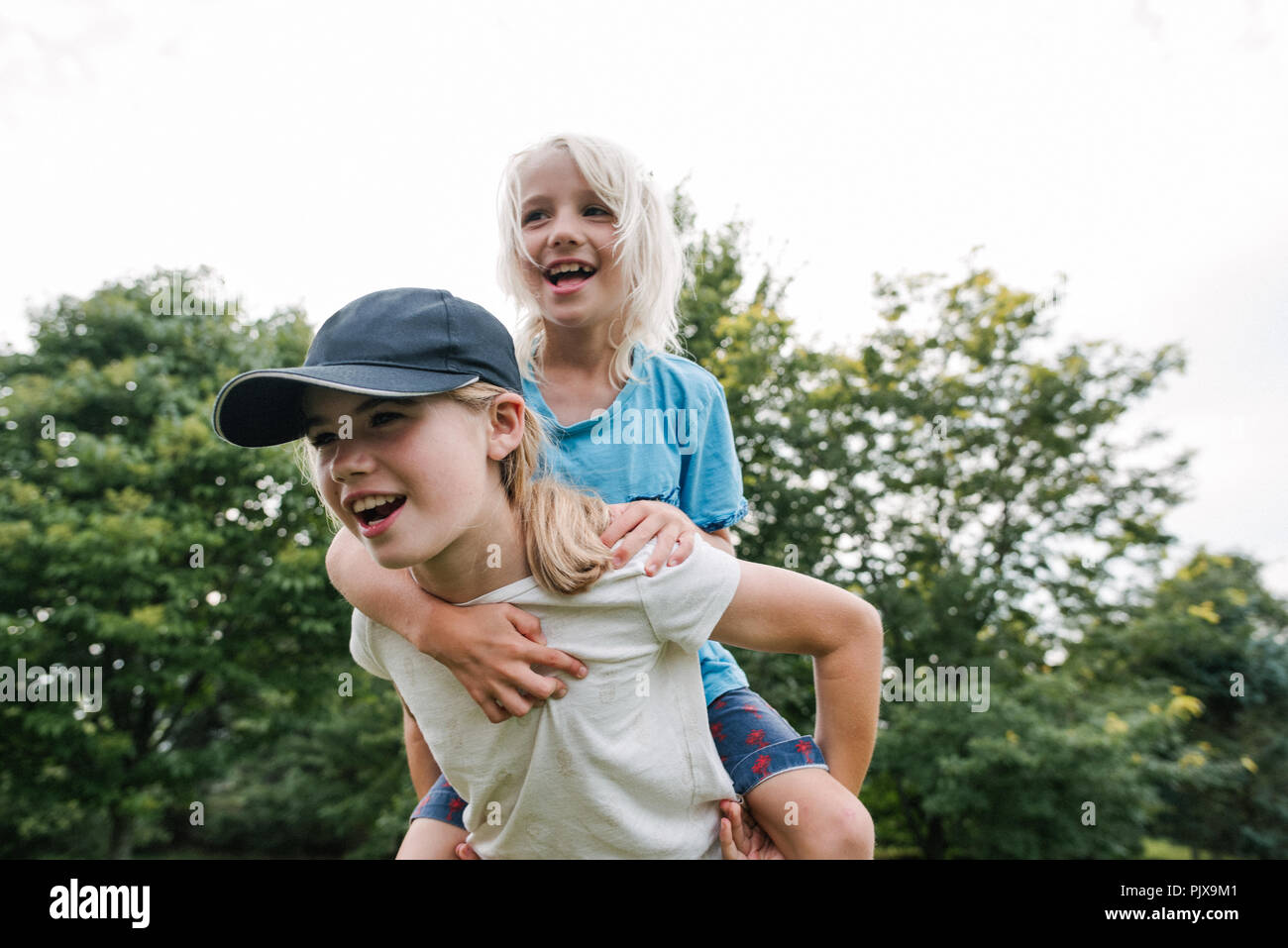 Children playing piggyback in park Stock Photo - Alamy