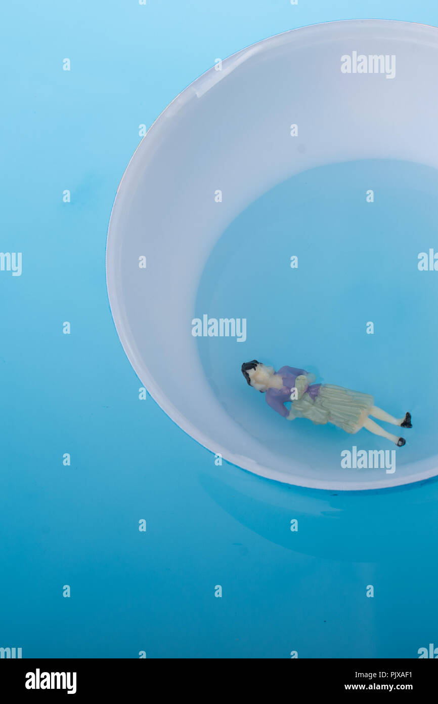 Little model globe with figurine floating in blue water Stock Photo - Alamy