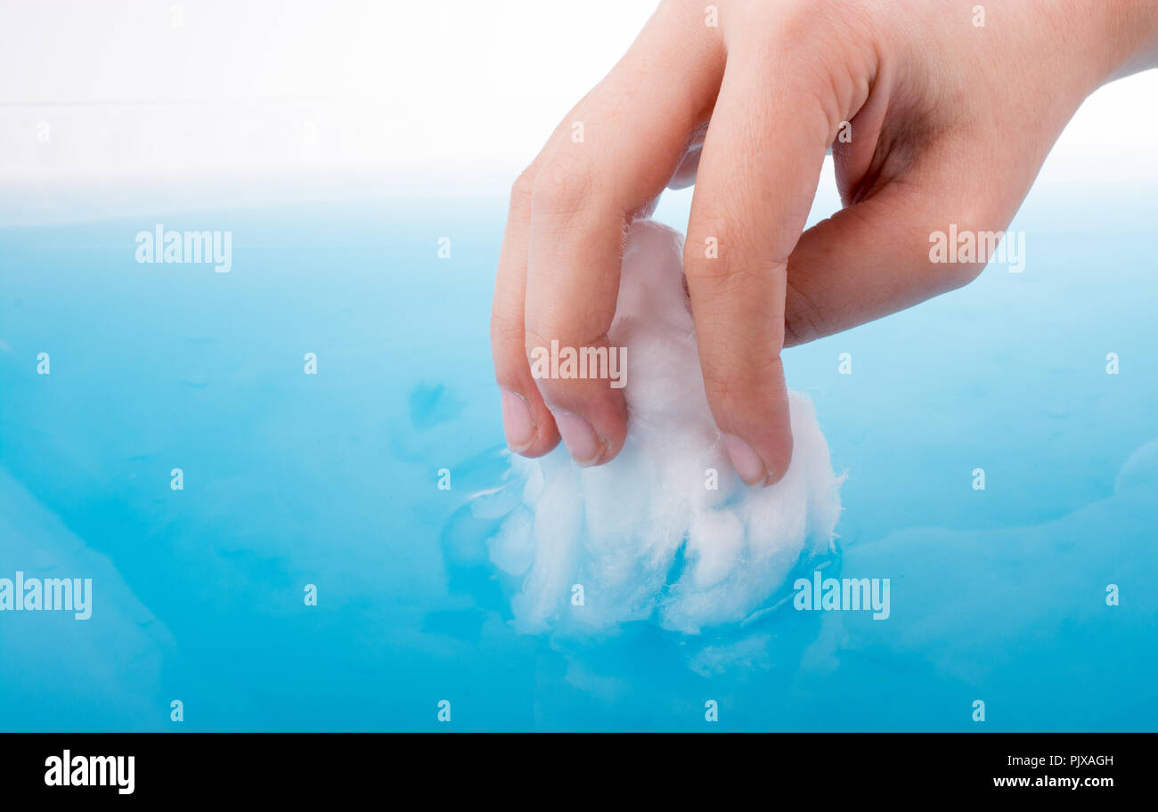 Hand holding some cotton in blue water Stock Photo - Alamy
