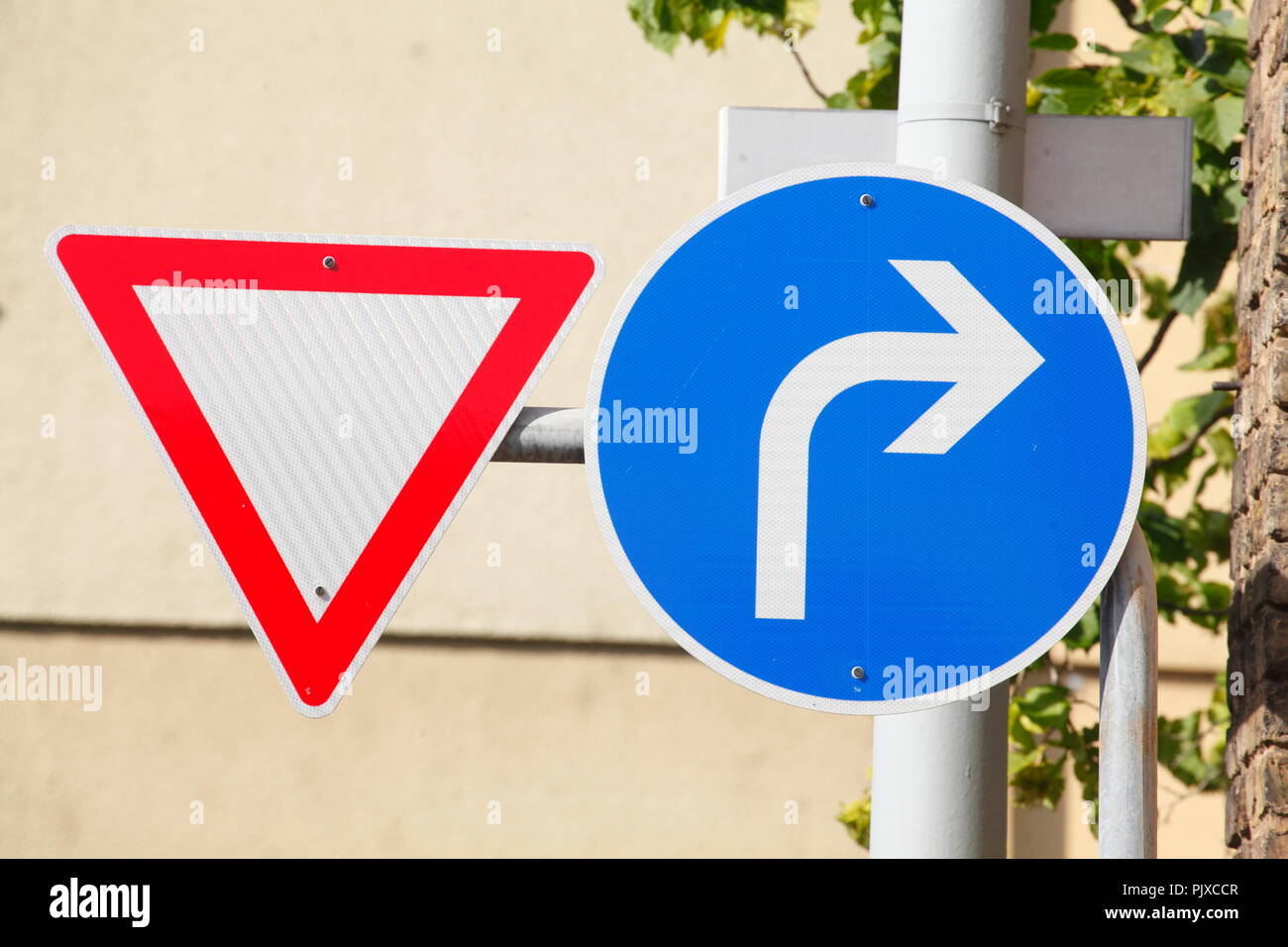 Follow traffic signs for right of way, turn right Stock Photo - Alamy