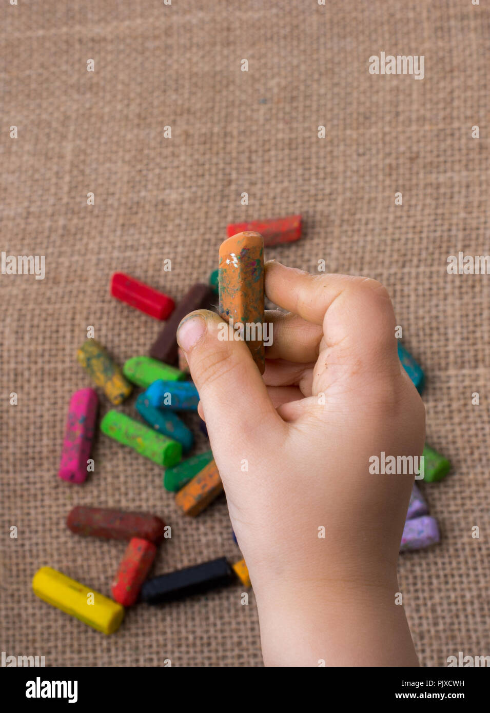 Used color crayons and a toddlers hand holding one Stock Photo - Alamy