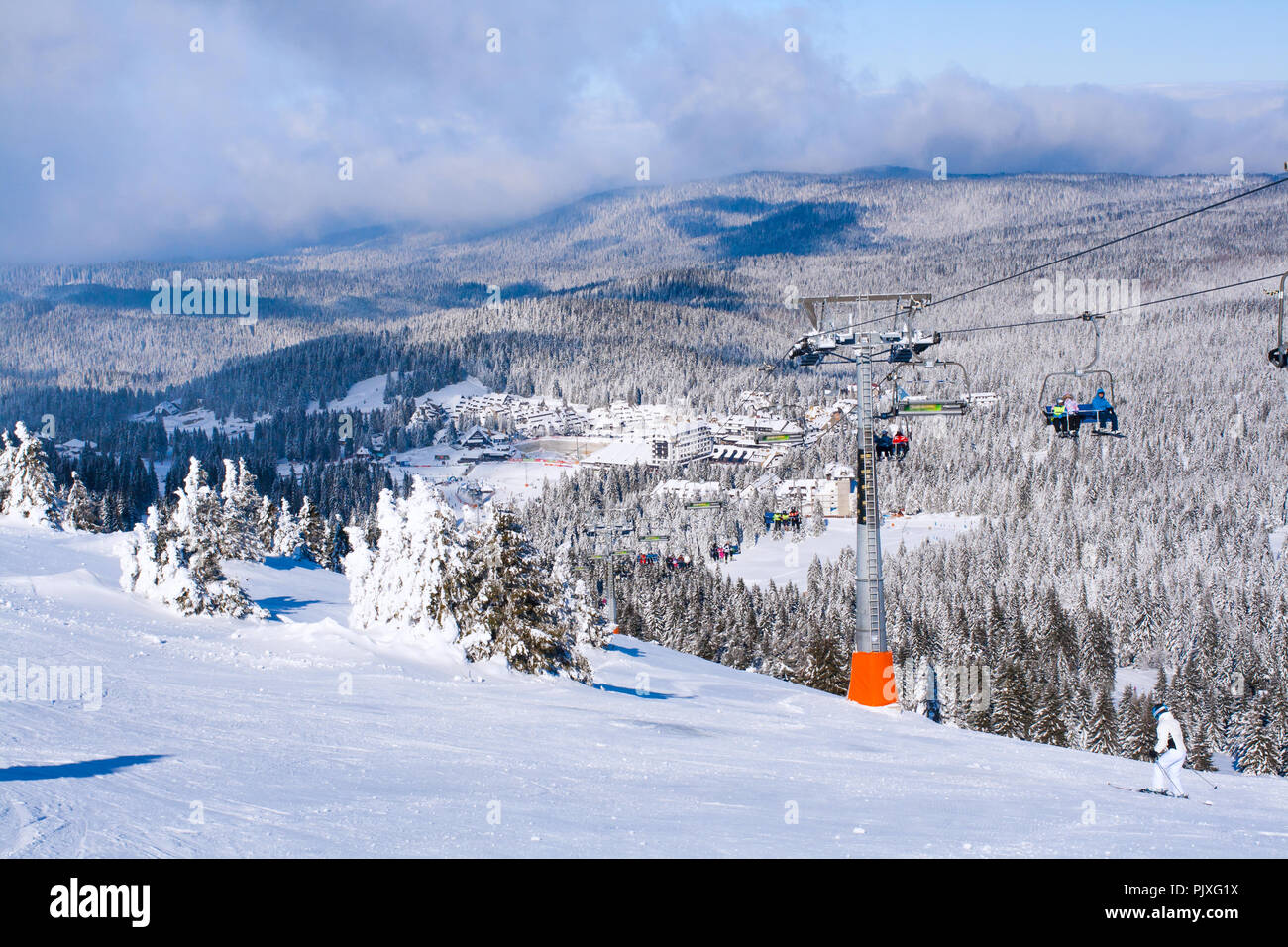 Ski resort, ski slope, people on the ski lift, mountains, houses and ...