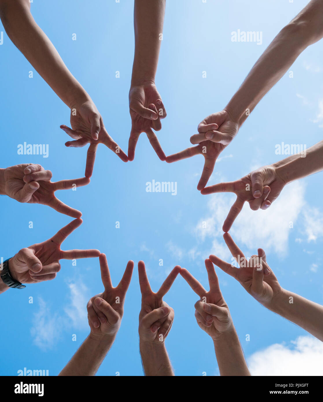 a circle of ten hands making peace signs under a blue sky with white ...