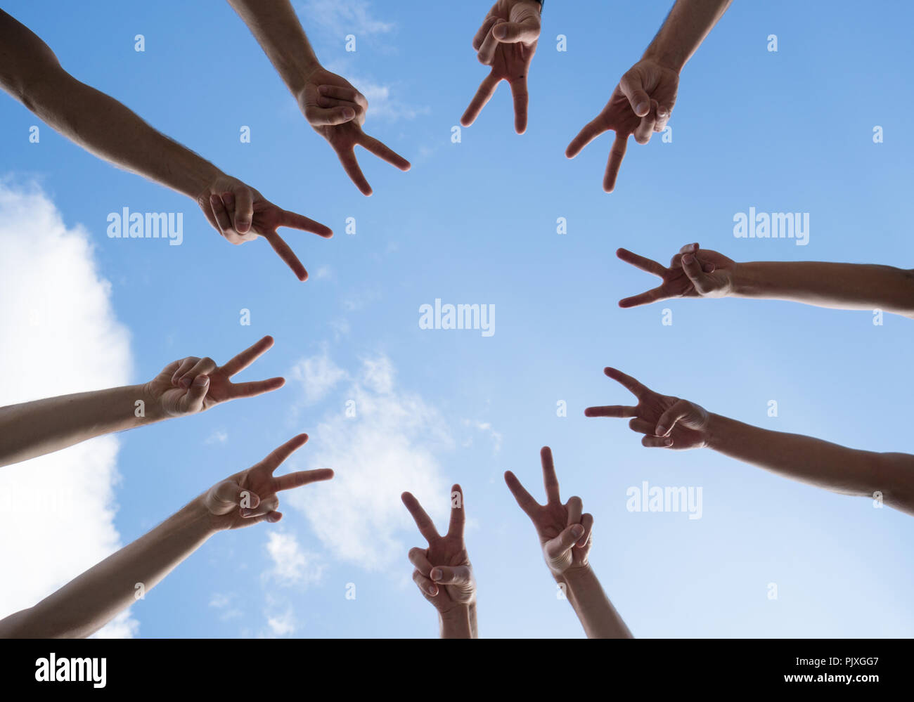 a circle of ten hands making peace signs under a blue sky with white ...