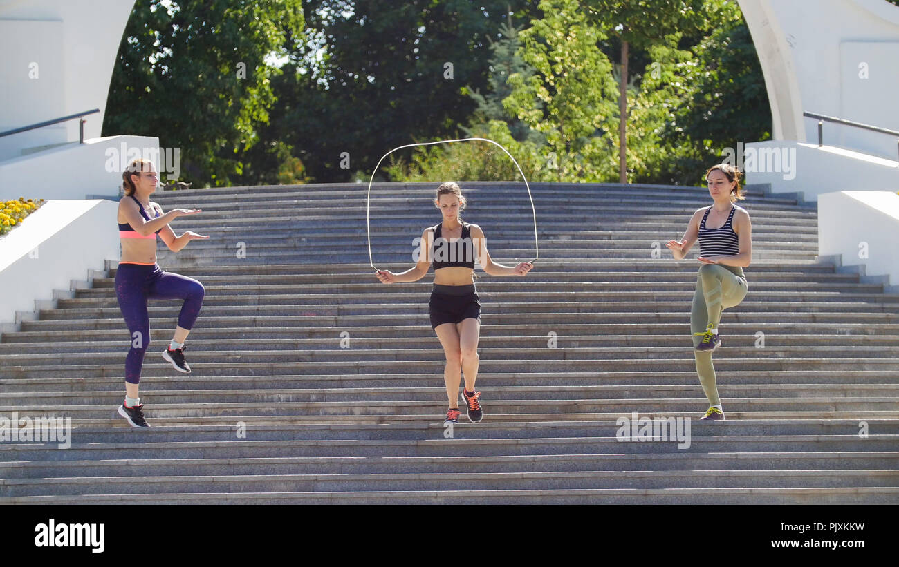 Three sports girls jump on the steps, one of them jumps on a rope Stock ...