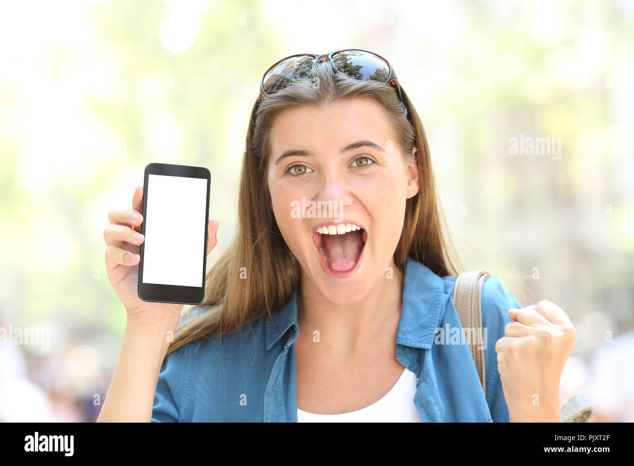 Front view portrait of a excited woman showing a smart phone screen ...