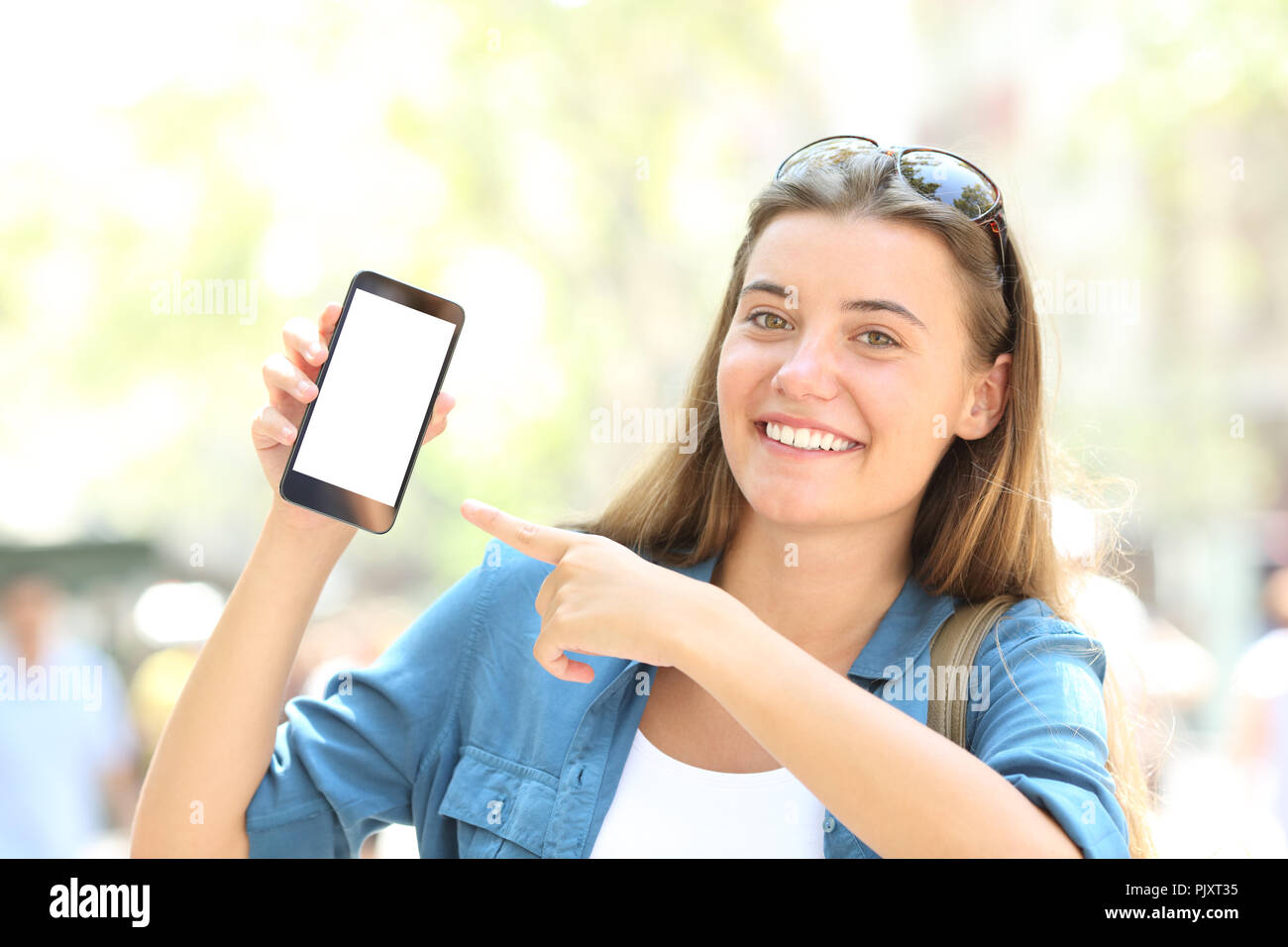 Smiley girl pointing to a blank smart phone screen mock up in the ...