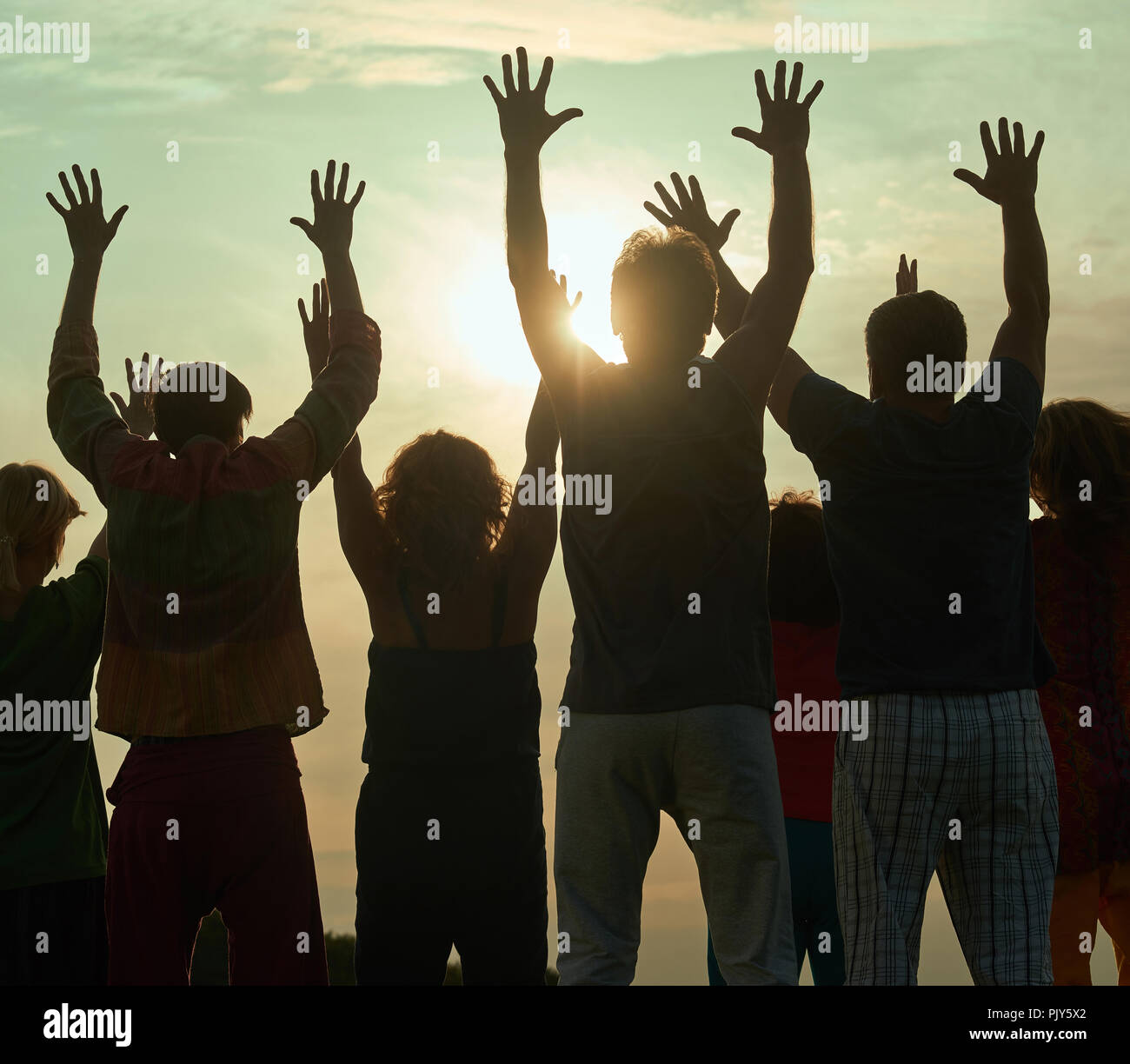 People stands on against a sun with heaved up hands Stock Photo - Alamy