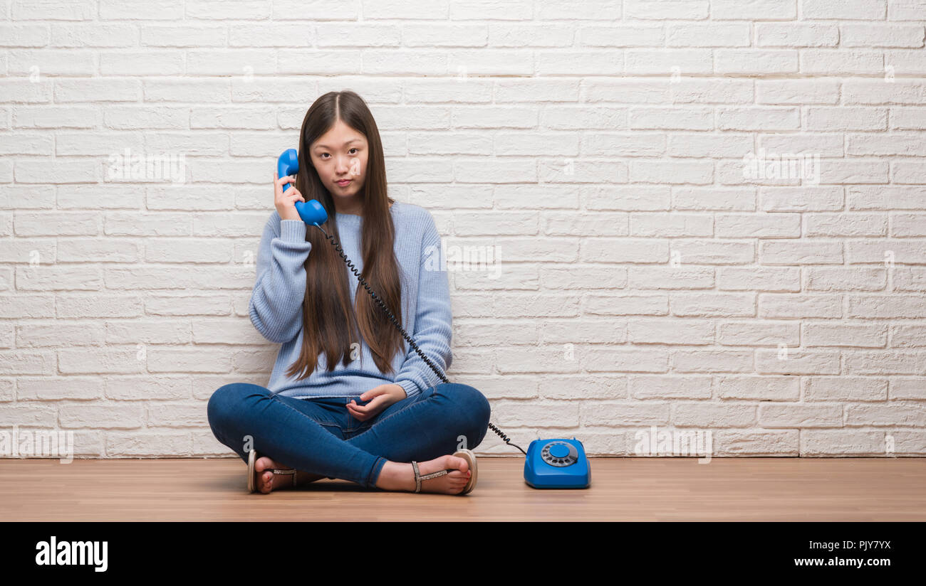 Young Chinese woman calling using vintage telephone with a confident ...
