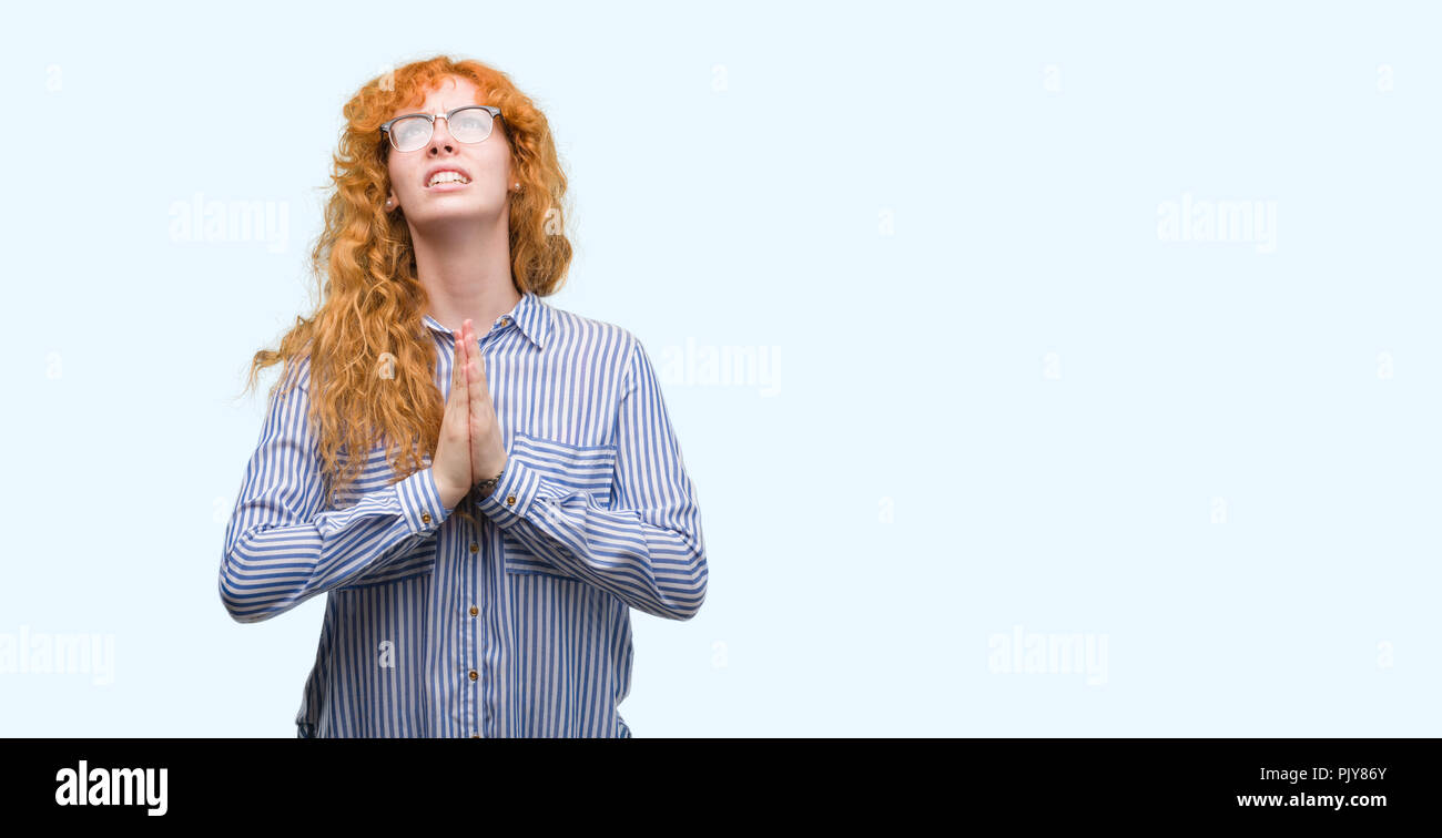 Young redhead bussines woman begging and praying with hands together ...