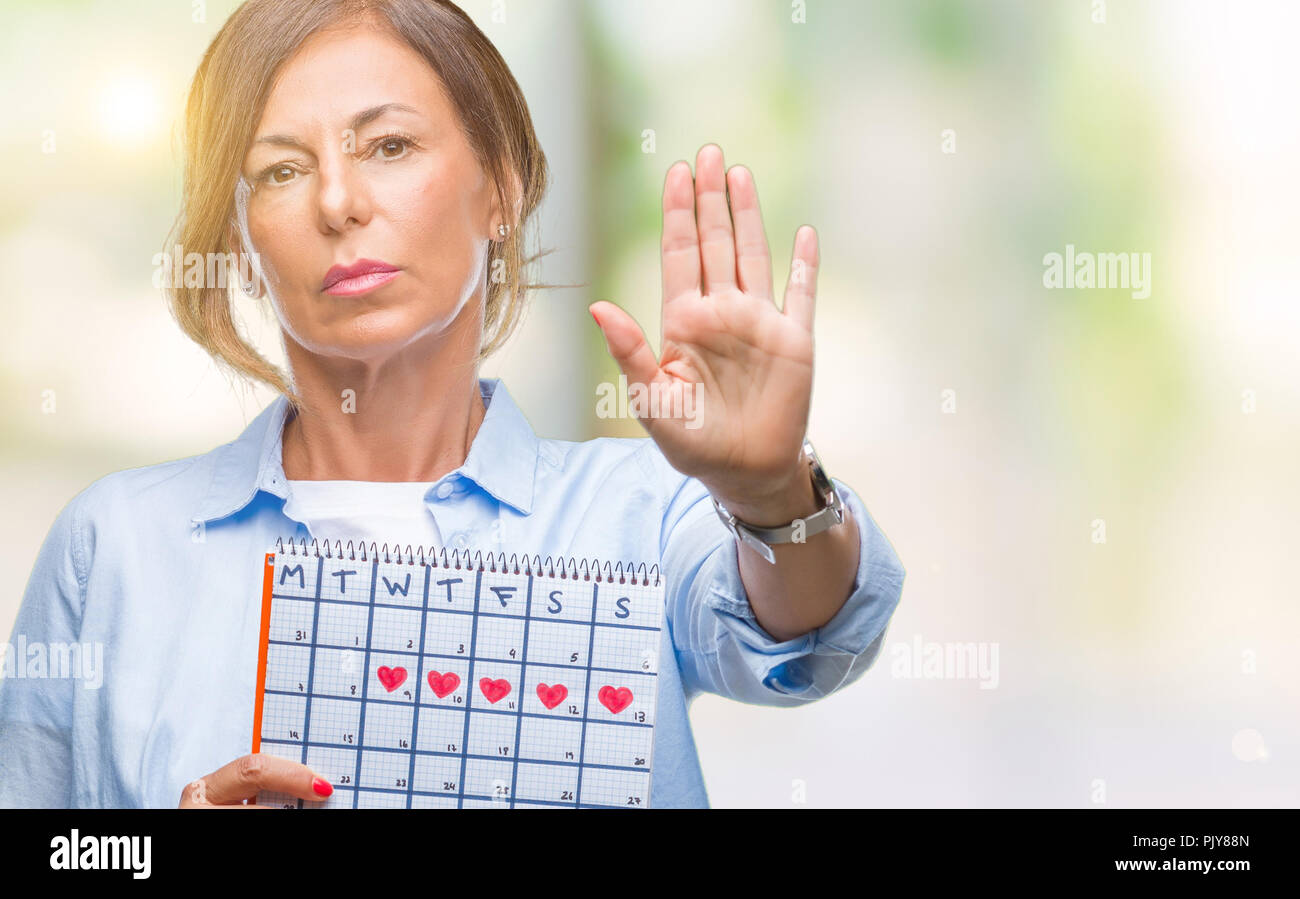 Middle age senior hispanic woman holding menstruation calendar over ...