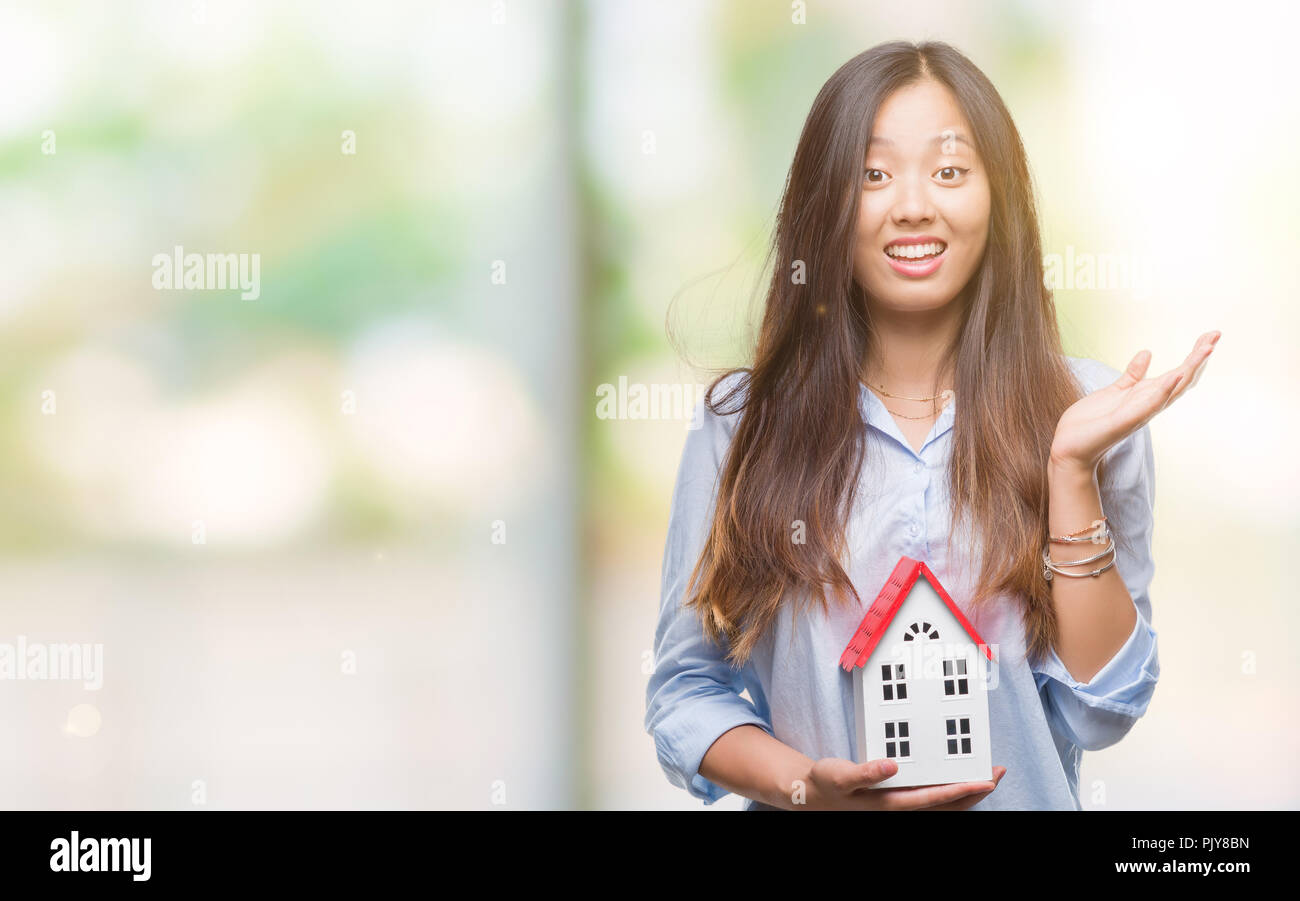 Young asian woman real state agent holding house isolated background ...