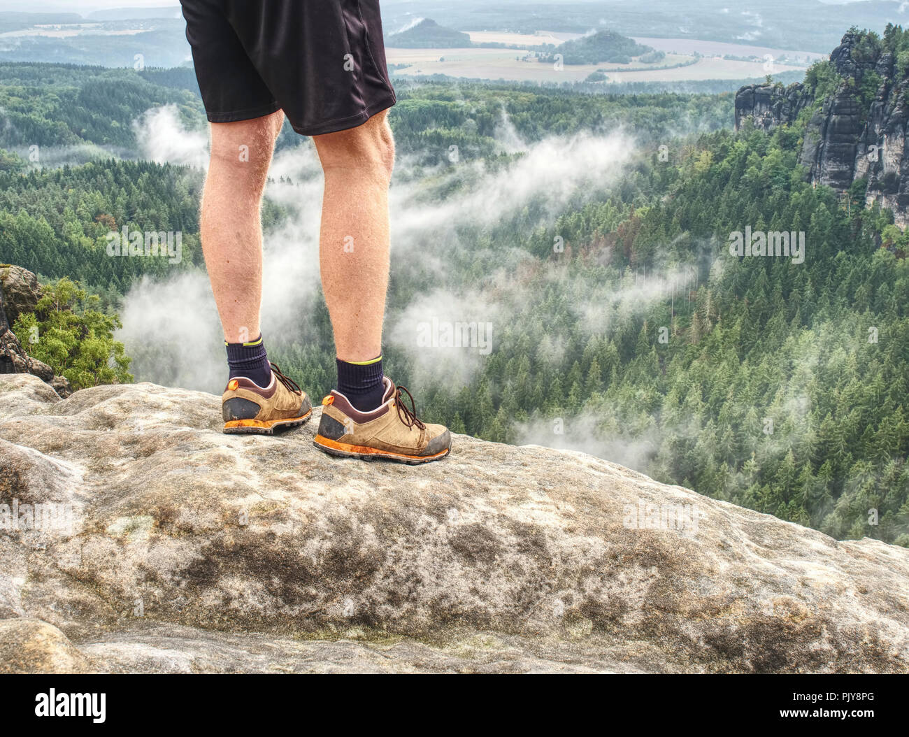 Hiker legs climbing on sunrise mountain peak rock. Slim legs of a ...