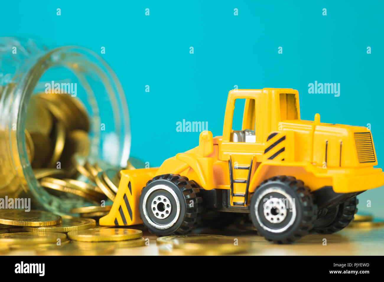 Mini bulldozer truck loading stack coin with pile of gold coin to glass ...