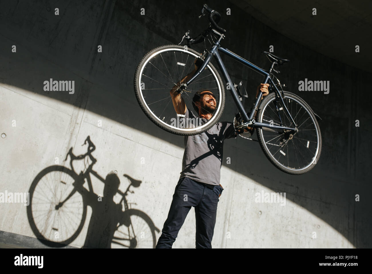 Young urban male pushing his bicycle up in the air and celebrating ...