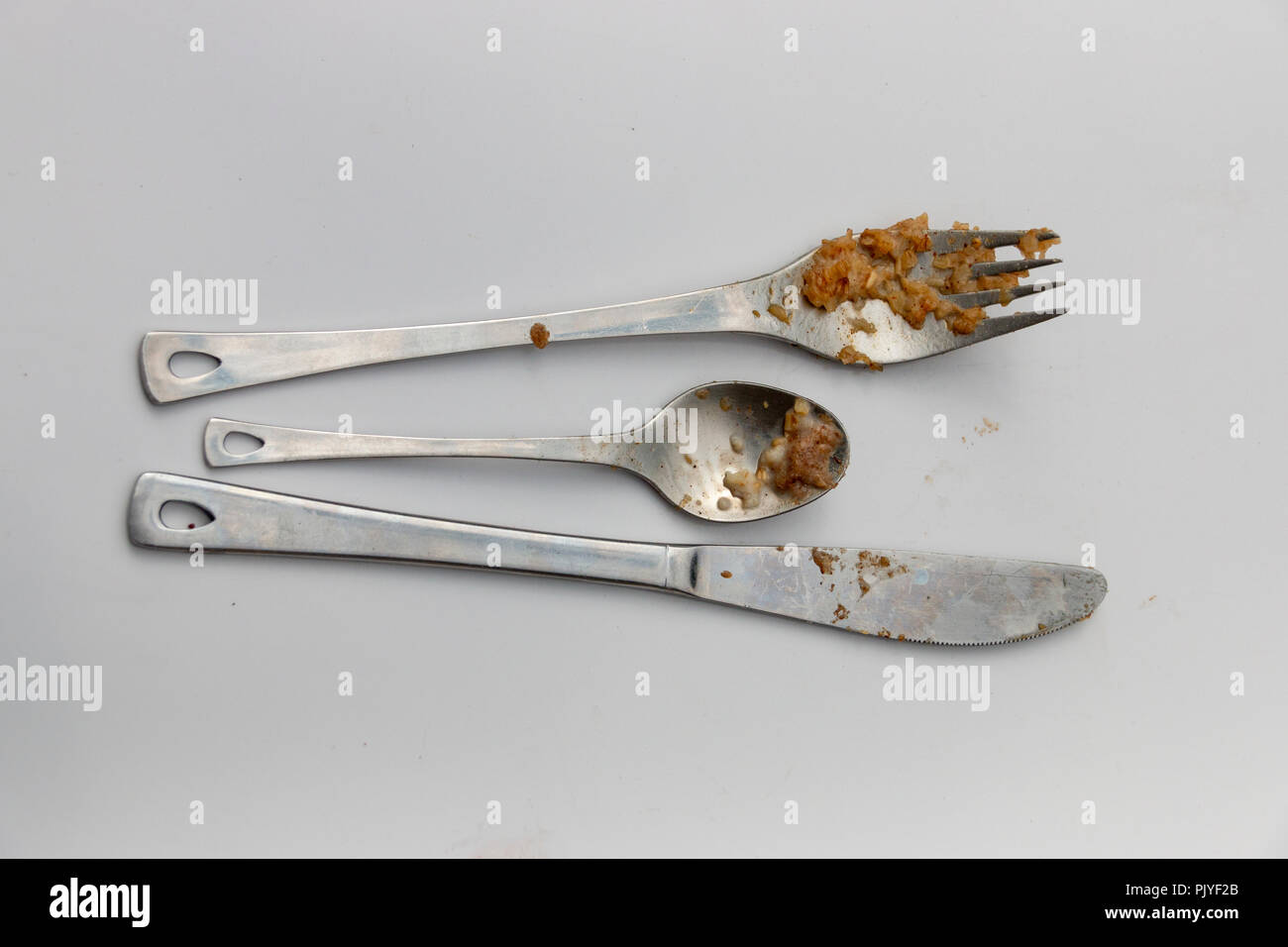 A close up view of dirty silver small spoon, knife and fork next to ...