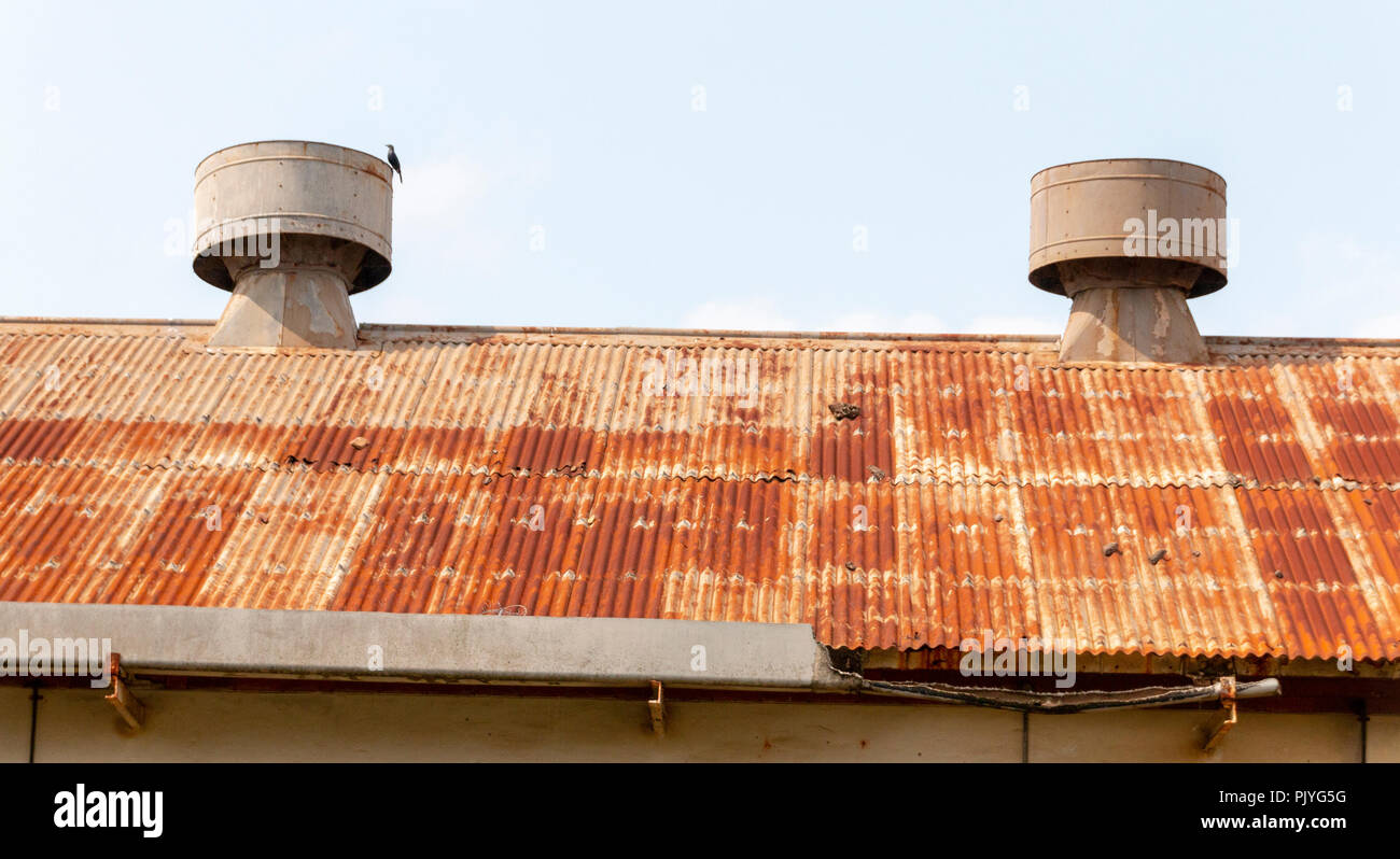Two metal air vents on a rusted old steel roof of an abandened buiding ...
