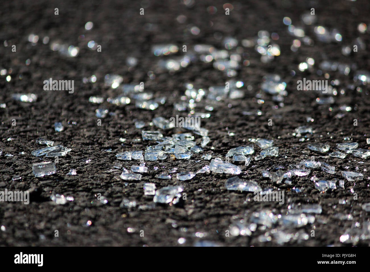 transparent shards of a windshield from the car on asphalt of parking ...