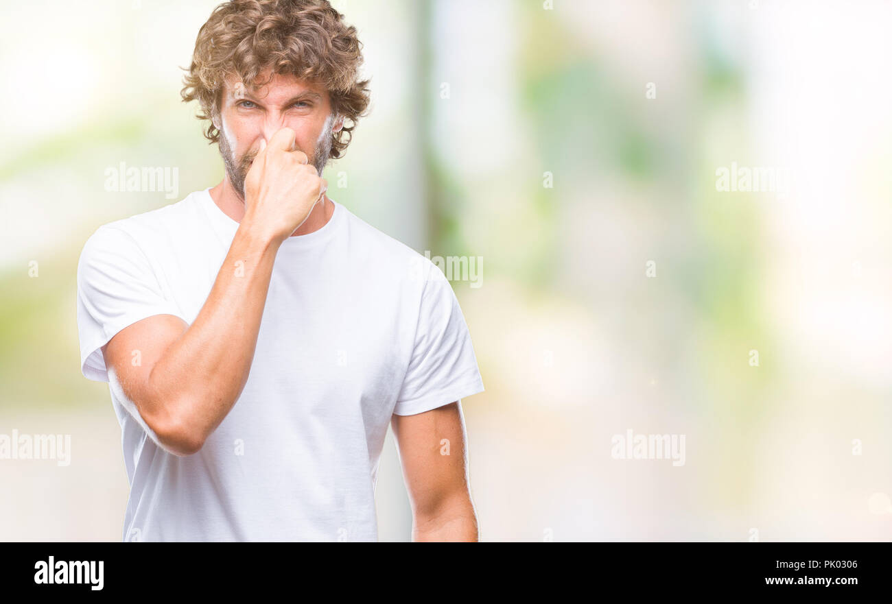 Handsome hispanic model man over isolated background smelling something ...