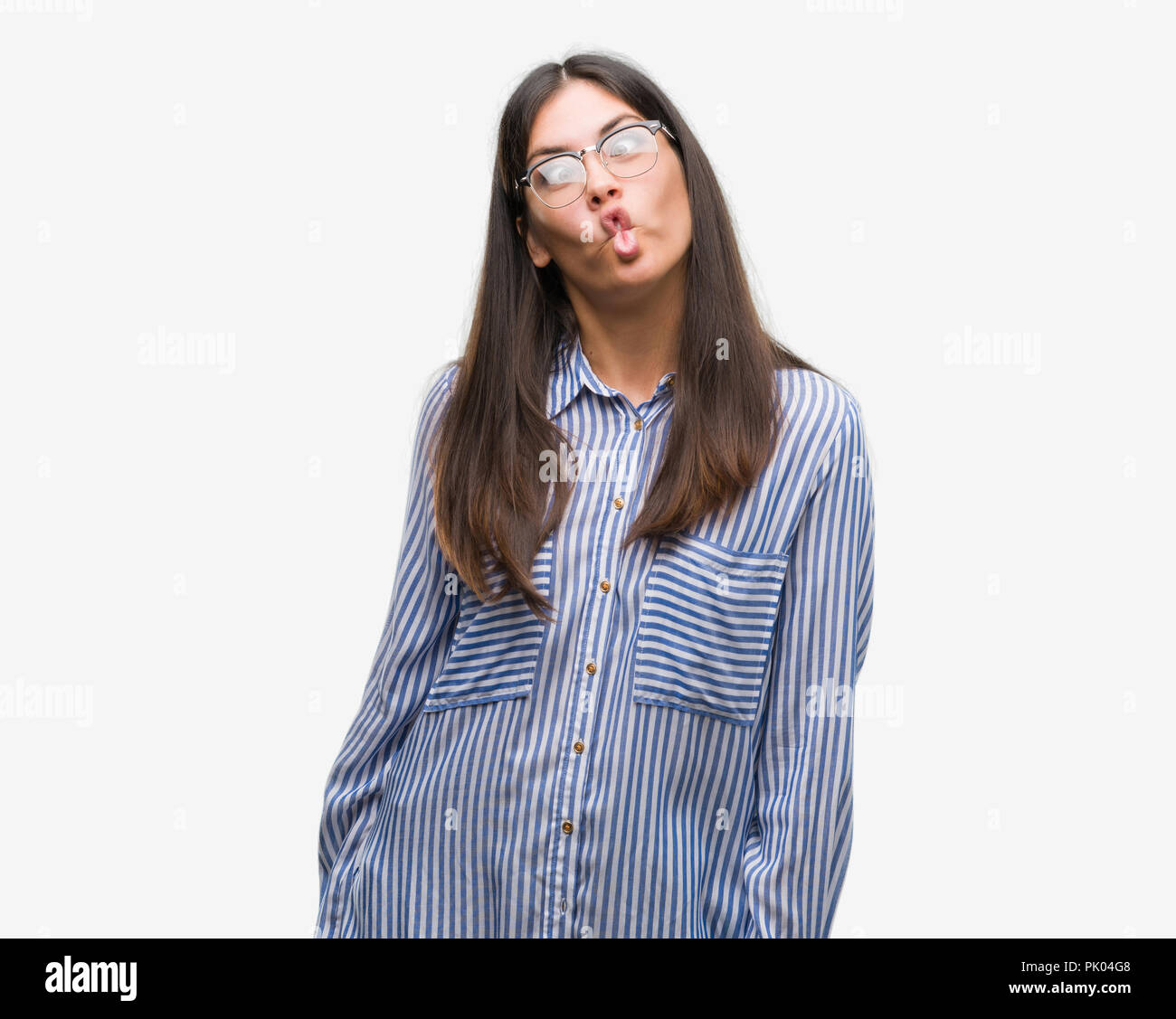 Young beautiful hispanic business woman making fish face with lips ...