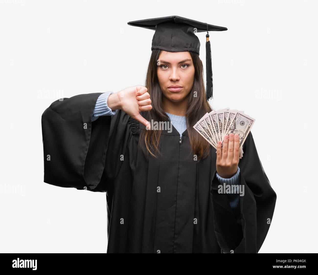 Young hispanic woman wearing graduated uniform holding dollars with ...