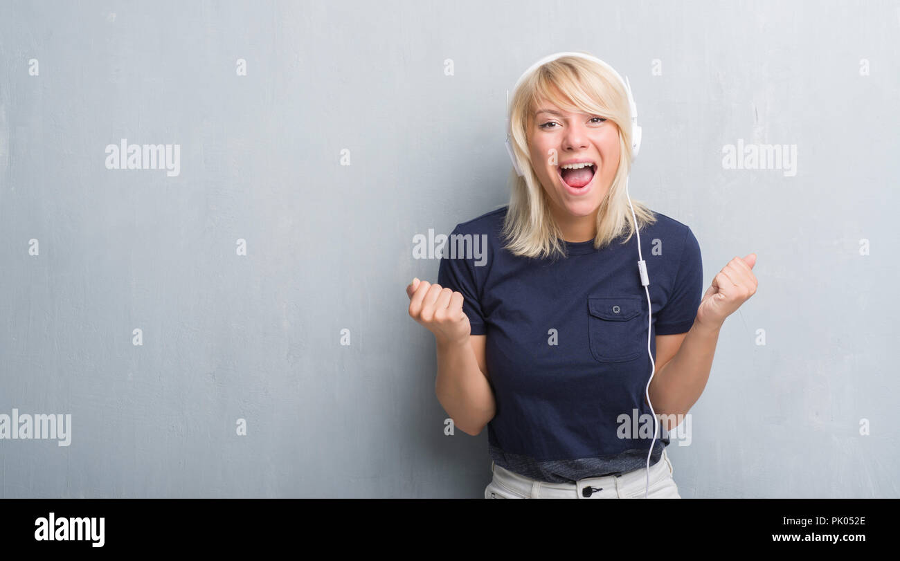 Adult caucasian woman over grunge grey wall wearing headphones ...