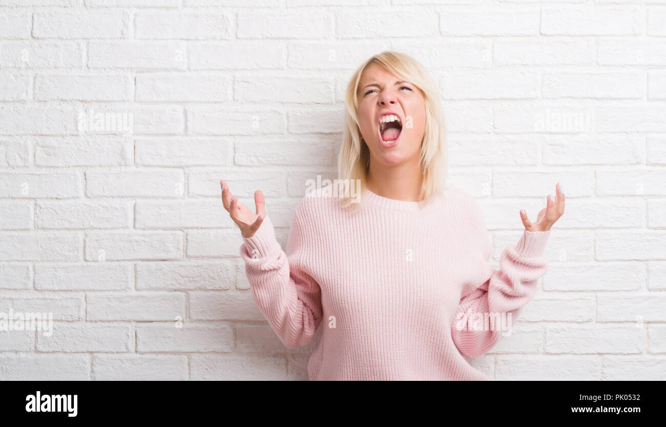 Adult caucasian woman over white brick wall wearing winter sweater ...