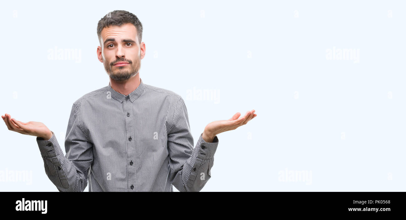 Young hipster man clueless and confused expression with arms and hands ...