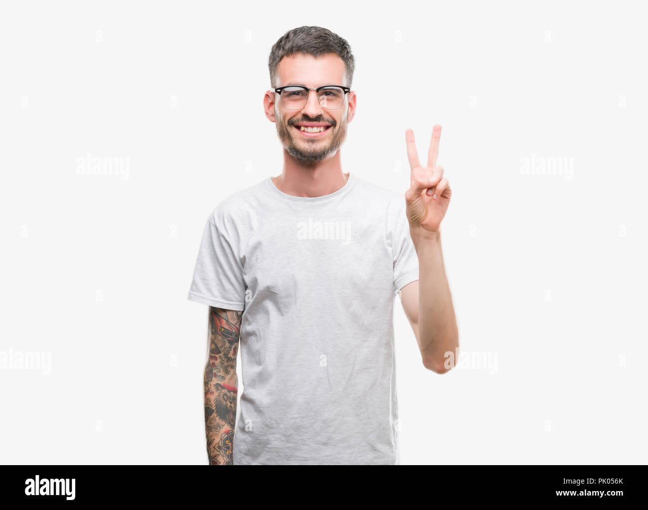Young tattooed adult man smiling looking to the camera showing fingers ...