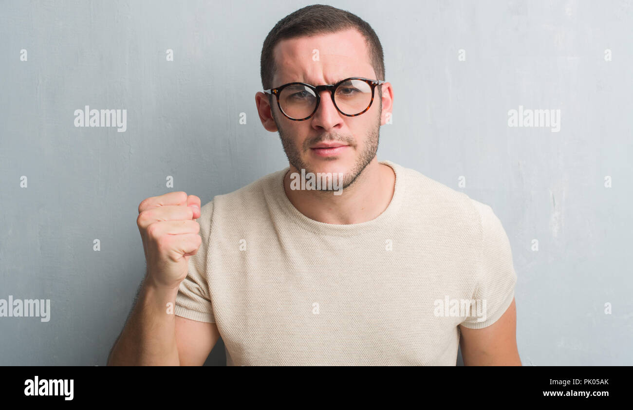 Young caucasian man over grey grunge wall annoyed and frustrated ...