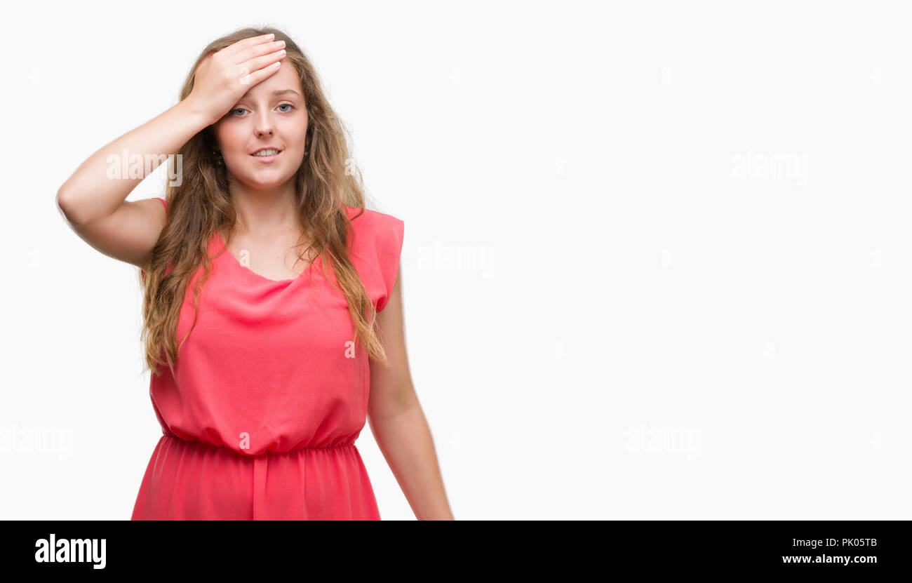 Young blonde woman wearing pink dress stressed with hand on head ...