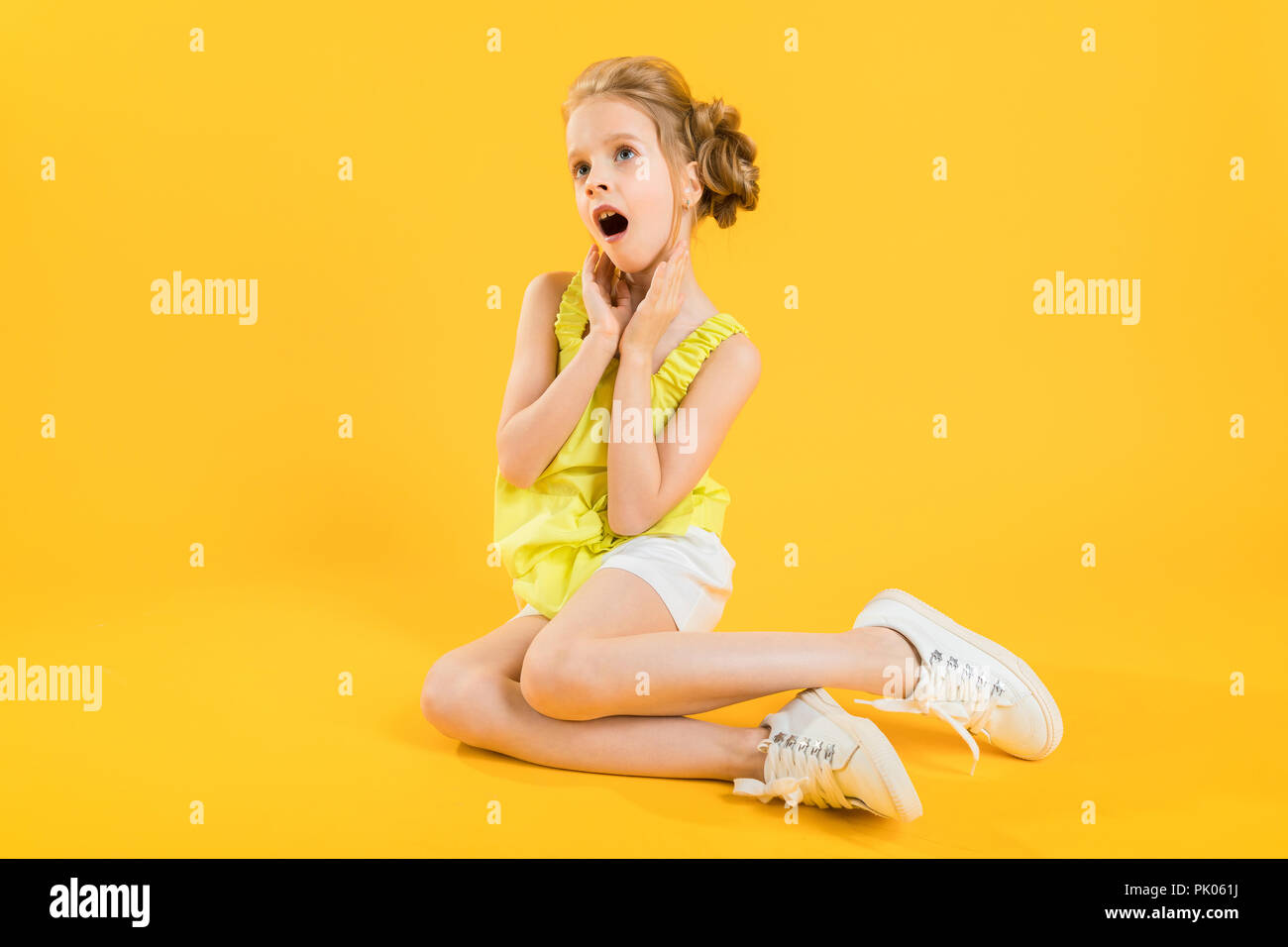 Portrait of a girl in white shorts and a yellow topic Stock Photo - Alamy
