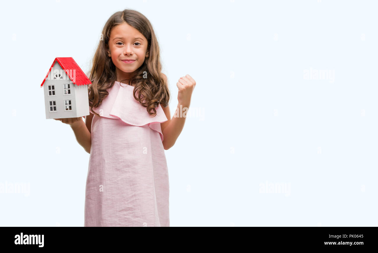 Brunette hispanic girl holding little house screaming proud and ...