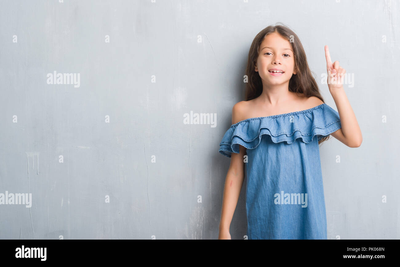 Young hispanic kid over grunge grey wall showing and pointing up with ...