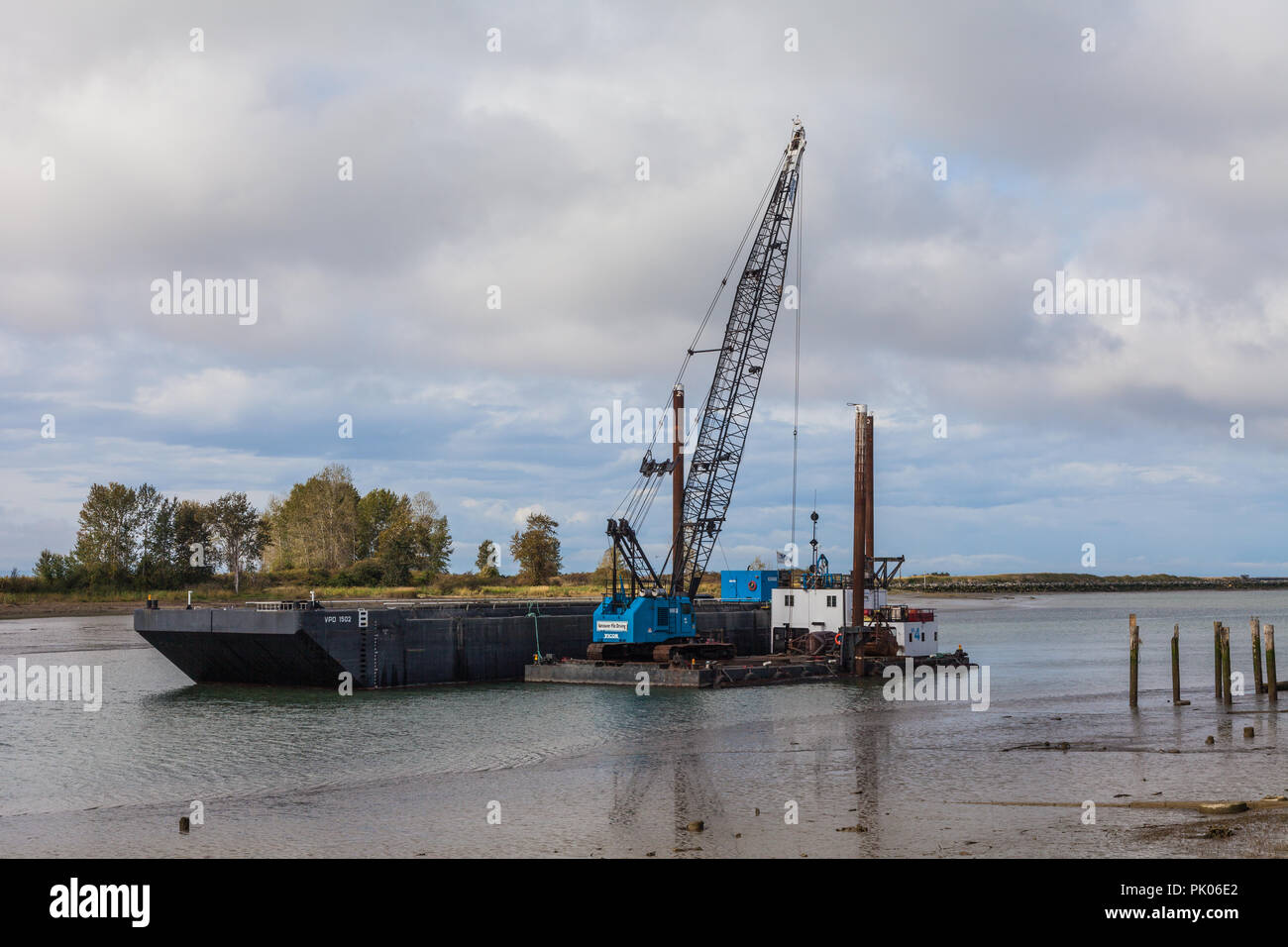 Floating dredging barge on the Fraser River with an empty debris barge ...