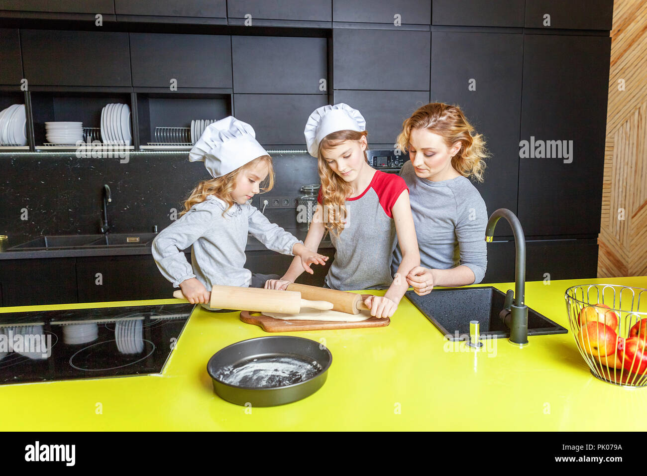 Happy family in kitchen. Mother and two children preparing dough, bake ...