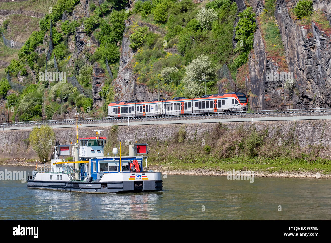 High speed train speeds past a barge travelling downstream on the Rhine ...