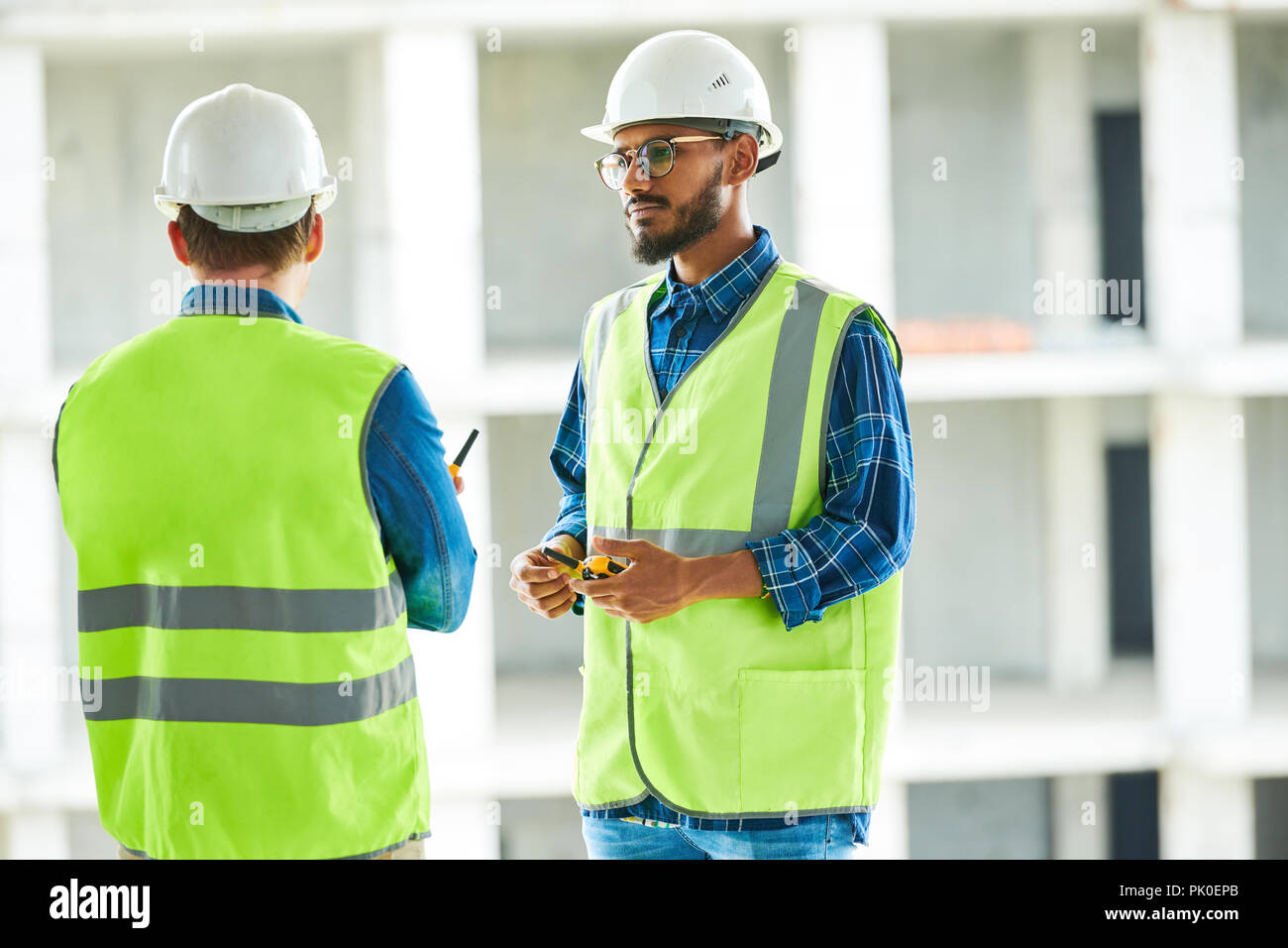 Confident worker listening to colleagues at apartment block site Stock ...