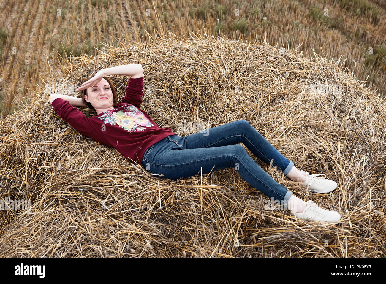 young girl having fun in the field, lying on a haystack Stock Photo - Alamy