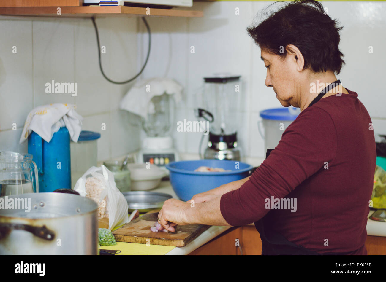 Senior woman preparing healthy home food from fresh vegetables in ...